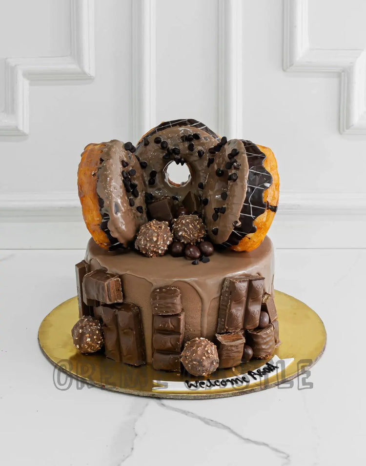 A chocolate sin cake full of chocolate with donuts also on top. A truly ...